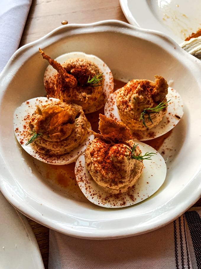 Deviled eggs topped with crispy bacon and fresh herbs—proof that perfection can still be improved upon. Like adding heated seats to a classic Cadillac.