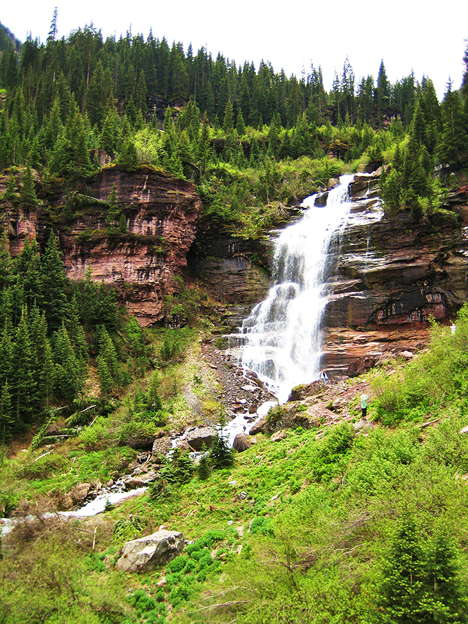 Bear Creek Falls cascades through layers of red rock like nature's own multi-tiered fountain. The reward for hikers who venture beyond Main Street's comforts.