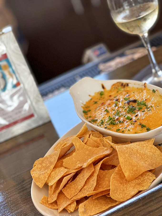 The crab and artichoke dip arrives like molten gold, ready to transform ordinary tortilla chips into vehicles of extraordinary pleasure.