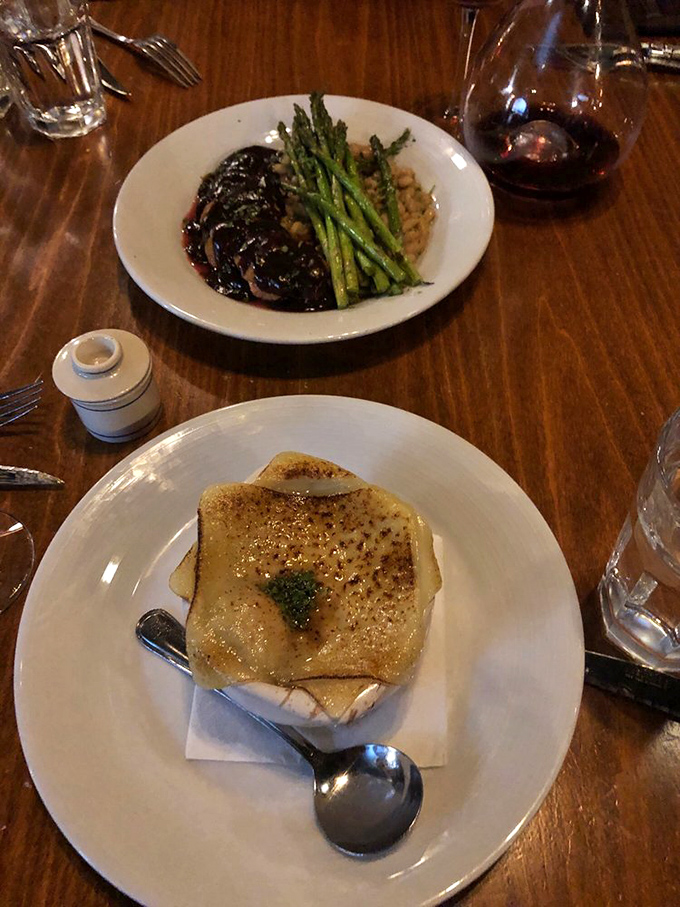 A symphony on a plate: duck glistening with reduction alongside French onion soup&mdash;proof that some duets were meant to be.