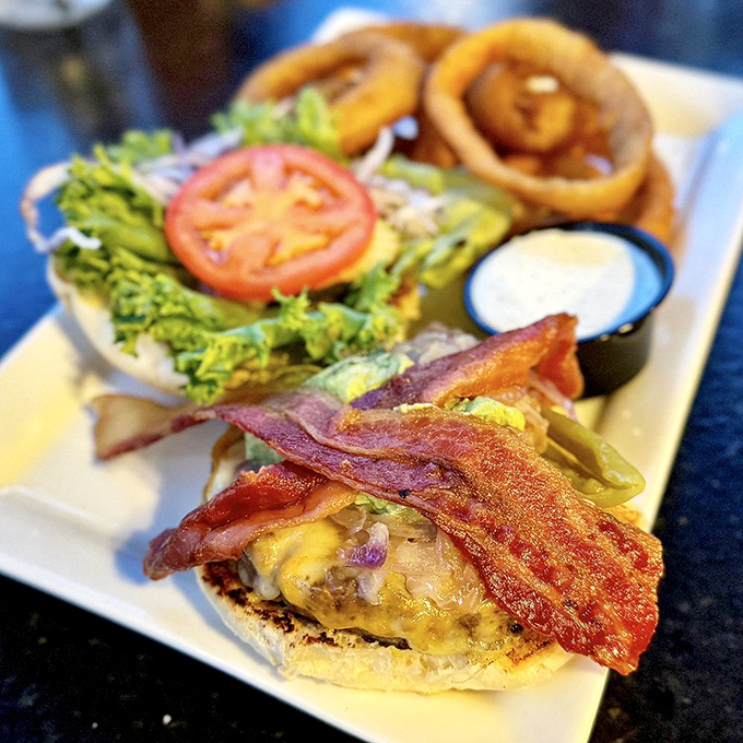 The Haunted Burger arrives with bacon standing at attention like it's guarding the flavor fortress beneath. Those onion rings? Halos for burger angels.