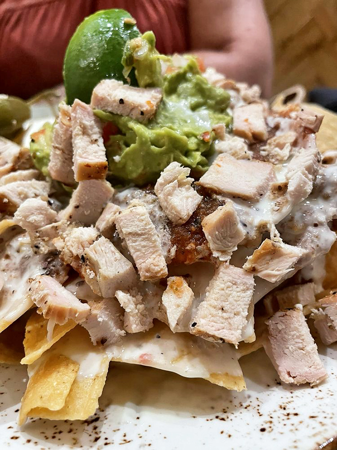Nachos that solve the age-old problem of topping distribution—every chip gets its fair share of chicken, guacamole, and that lime wedge's citrusy blessing.
