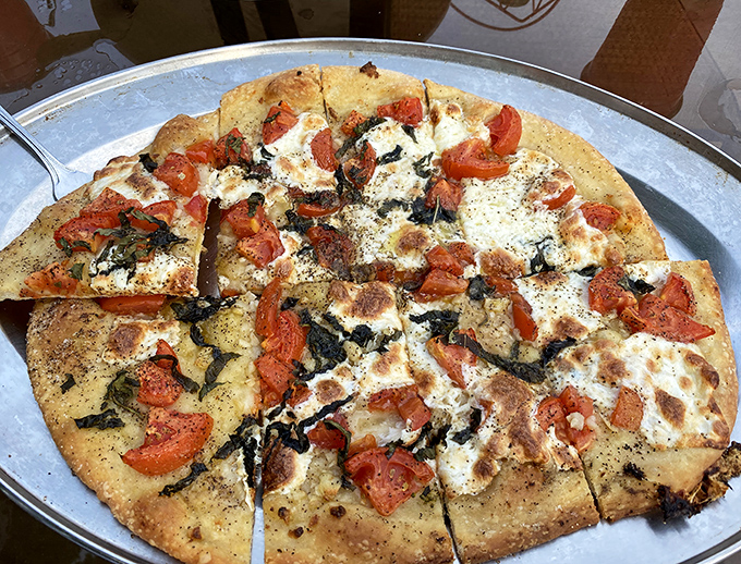 Fresh tomatoes and herbs dance across this artisanal pie like they're auditioning for "So You Think You Can Pizza." Spoiler alert: they got the part.