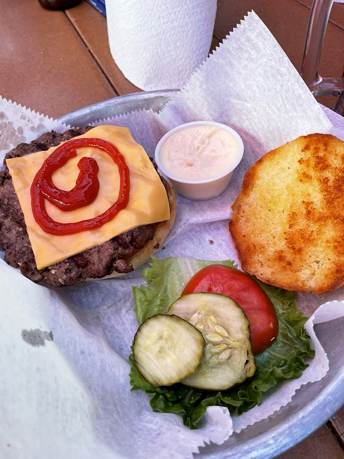 The artistic spiral of ketchup transforms this juicy burger from mere food into an edible work of art that demands to be photographed—then devoured.