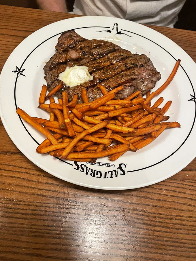A perfectly grilled steak topped with butter meets sweet potato fries. This plate isn't just dinner&mdash;it's what food dreams are made of.