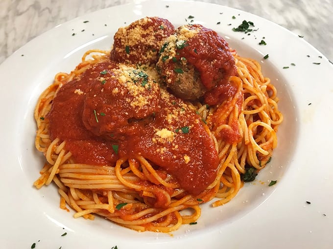 Three perfectly formed meatballs standing proud atop a swirl of spaghetti. This isn't just dinner; it's edible architecture with a dusting of parmesan snow.