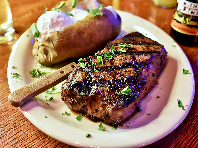 The classic steakhouse duet &ndash; a beautifully seared strip steak alongside a fluffy baked potato dressed in all its glory.