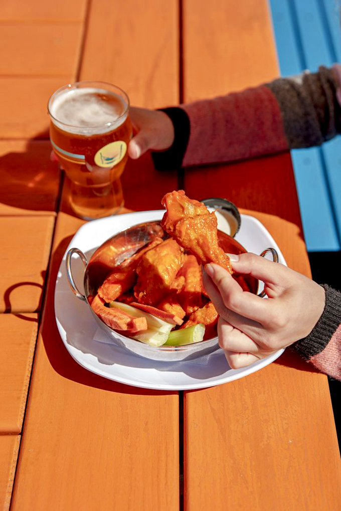 Wing perfection is a delicate science: crispy exterior, succulent interior, and that perfect harmony with an ice-cold beer on a colorful patio.