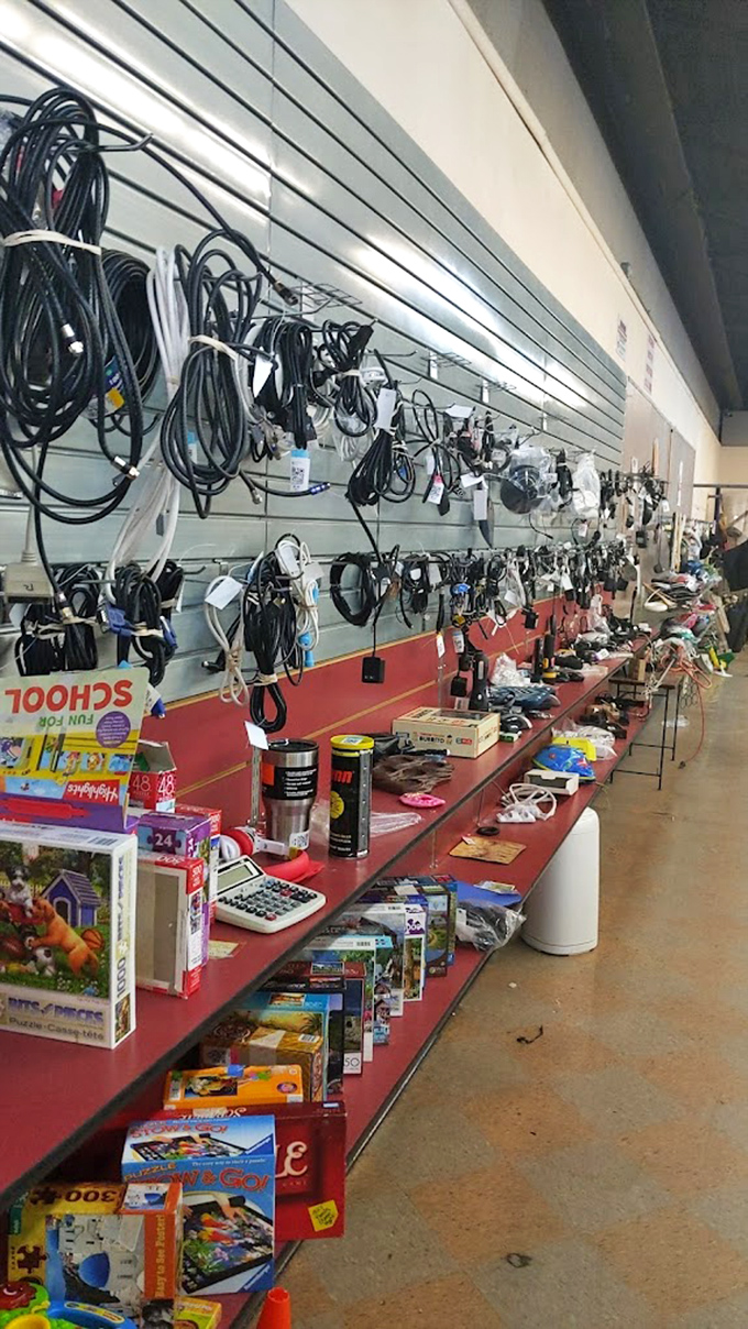 Cables and cords hang like technological vines in the electronics jungle, while puzzles and gadgets below offer analog entertainment alternatives.