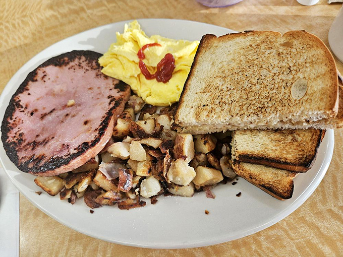 The holy trinity of breakfast: perfectly grilled ham, golden hash browns, and eggs that would make a chicken proud. Simple perfection needs no explanation.