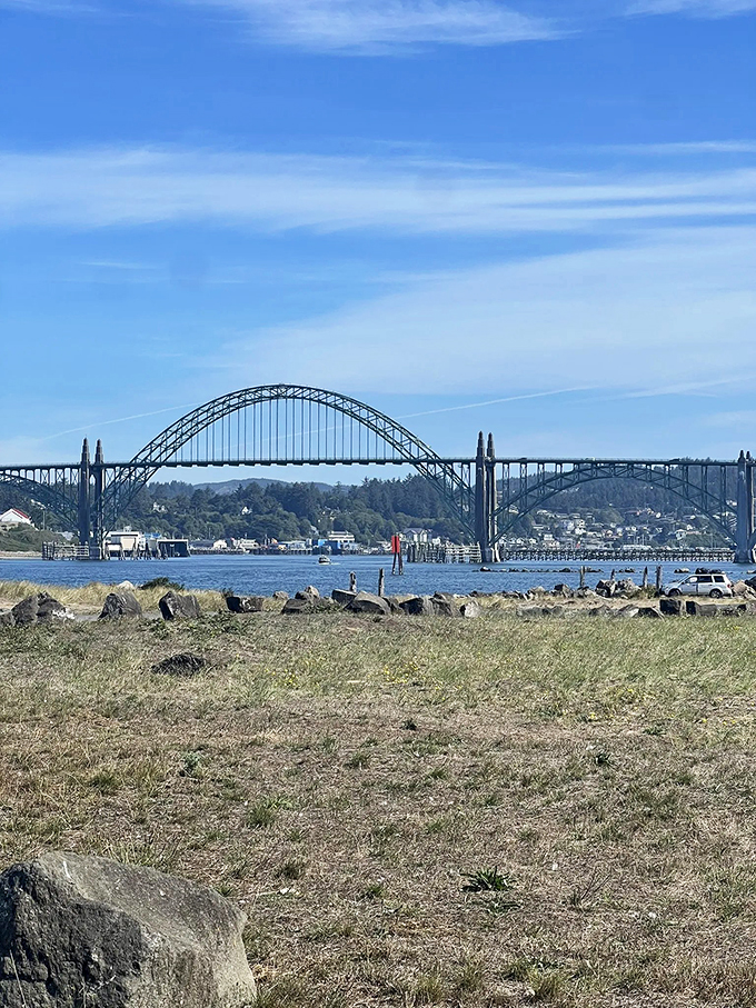 The iconic Yaquina Bay Bridge stands sentinel in the distance, a man-made marvel complementing nature's masterpiece along the South Jetty Trail. 