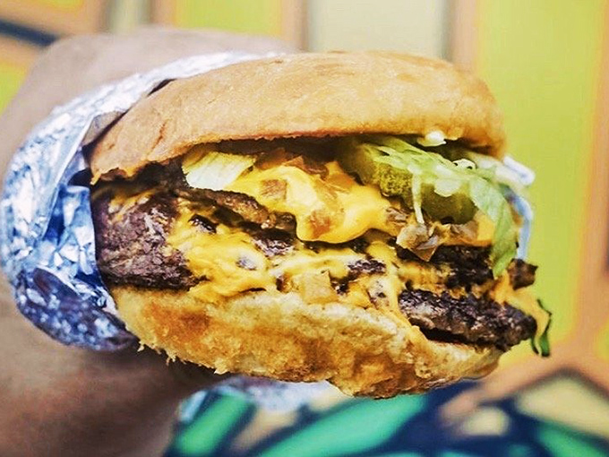 The melty cheese cascading down these patties isn't just topping a burger; it's creating a moment of pure culinary joy wrapped in foil.