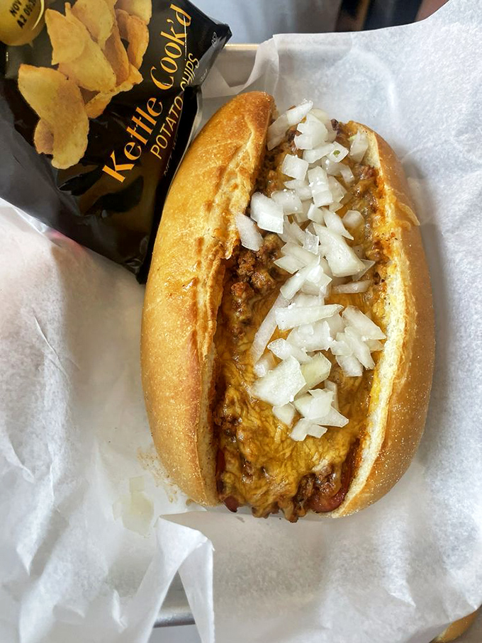 Melted cheese blankets this chili dog like a warm hug, while diced onions add that perfect crunch. Comfort food, elevated.