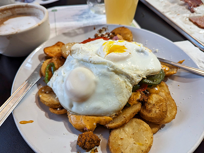 Breakfast architecture at its finest: crispy potatoes crowned with sunny-side-up eggs that seem to wink at you with golden approval.
