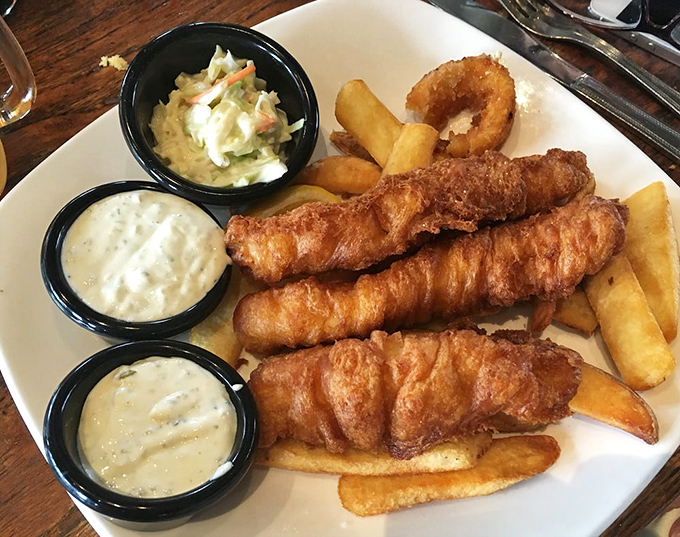Three perfect golden fish fillets standing at attention, flanked by crispy fries and creamy sides&mdash;a plate that demands both respect and immediate consumption.