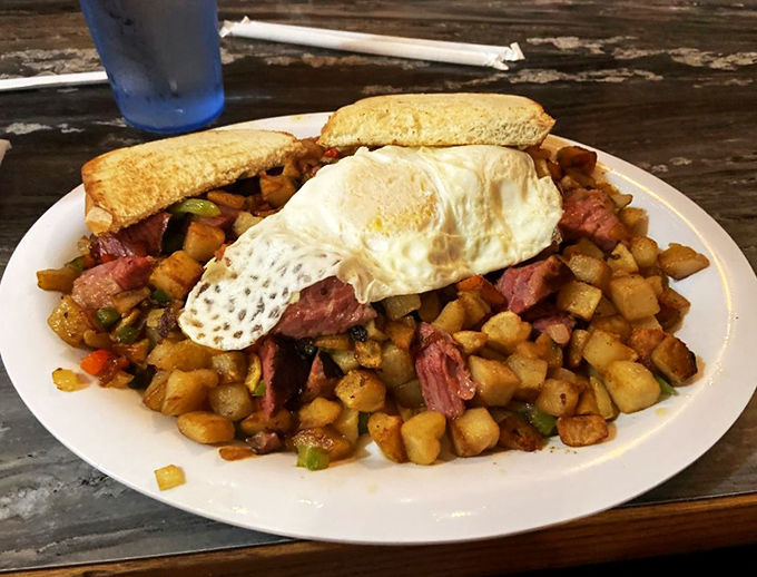 Breakfast architecture at its finest &ndash; a mountain of potatoes, meat, and vegetables with an egg sentinel standing guard on top.