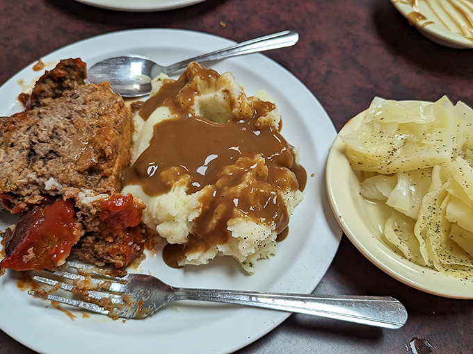Meatloaf, potatoes swimming in gravy, and tender cabbage on the side. The holy trinity of comfort food, arranged like a Renaissance painting on a humble white plate.