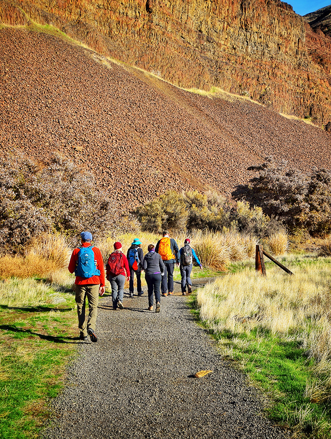 The trail gang heads into the canyon's embrace, their colorful backpacks like confetti against nature's earthy palette. Social distancing before it was trendy. 