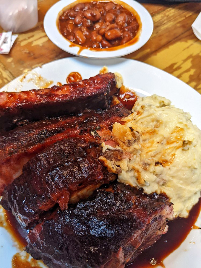 A barbecue trinity: ribs bathed in sauce, creamy mashed potatoes, and beans that have clearly been introduced to some smoked meat along the way.