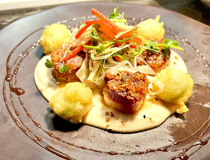 Scallops that could make Poseidon himself jealous. Perfectly seared and nestled on a creamy canvas with crispy accents&mdash;seafood elevated to art form.