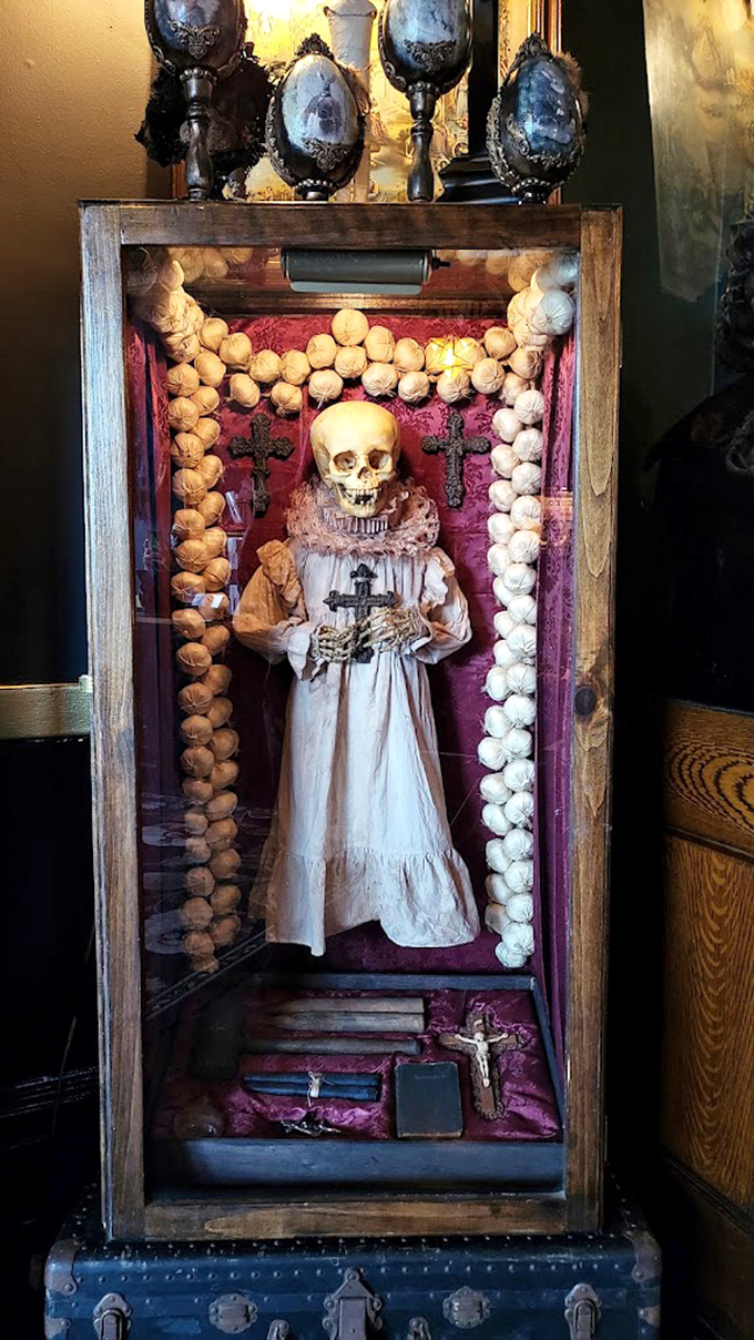 This memento mori display featuring a child-sized skeleton in period dress surrounded by rosary beads serves as a haunting reminder of Victorian mourning traditions and mortality art.