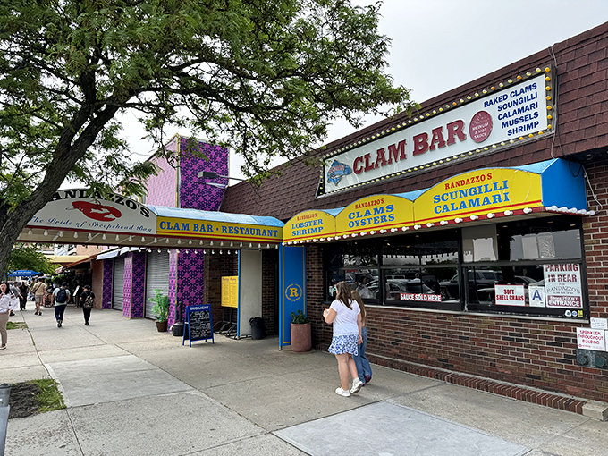 Randazzo's neon-bright "Clam Bar" sign glows like a beacon for Brooklyn seafood pilgrims seeking sauce-drenched calamari salvation.