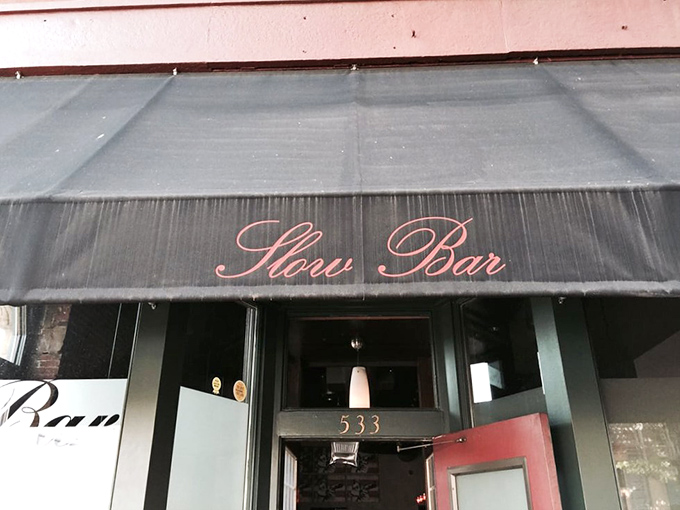 Slow Bar's moody interior sets the stage for burger magic. Red booths, brick walls, and burgers that deserve their own spotlight. 