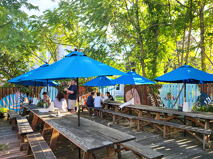 The wooden deck at Blue Pit transforms into a summer sanctuary where strangers become friends over shared appreciation of smoke and meat.