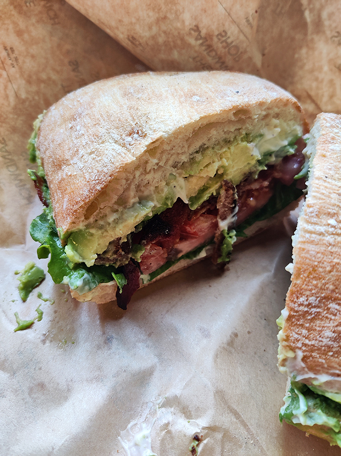 The cross-section reveals the sandwich's soul&mdash;avocado, bacon, and fresh greens nestled between bread that's achieved the perfect toast-to-softness ratio.