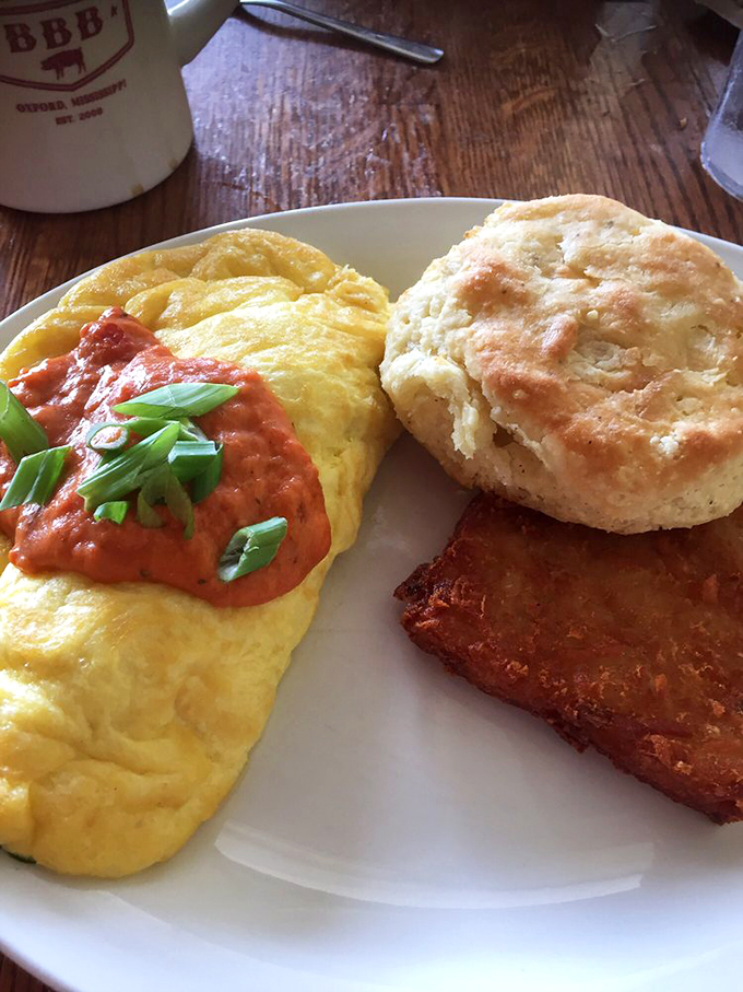 This isn't just an omelet; it's a sunrise captured in egg form, its tomato sauce glowing like morning itself, sidekicked by a biscuit that defies gravity.