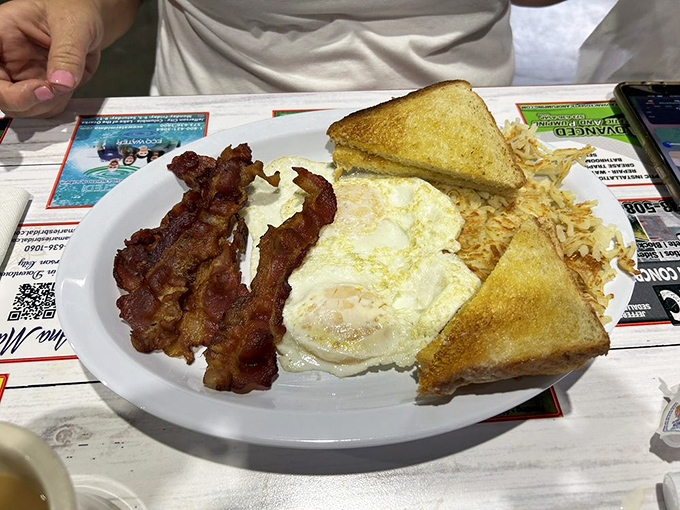The holy trinity of breakfast perfection: perfectly fried eggs, bacon with ideal crisp-chew balance, and golden hash browns.