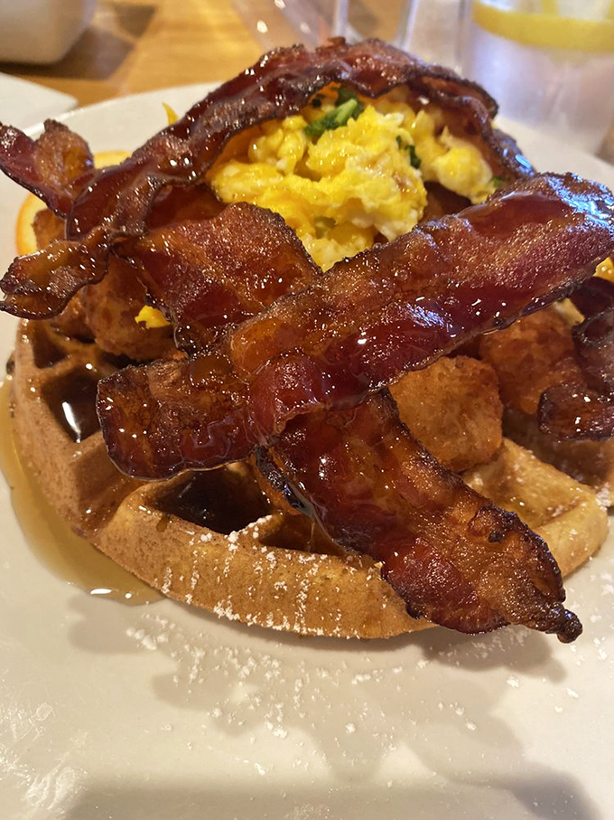Bacon arranged like a crown atop this waffle kingdom, with maple syrup ready for its royal duties. Breakfast architecture at its finest.