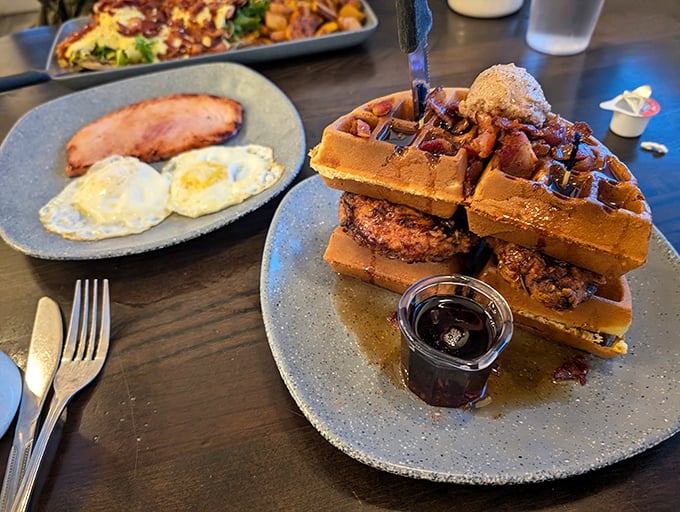 Architectural marvel meets breakfast brilliance: golden waffles stacked with crispy chicken and crowned with butter. Maple syrup standing by for the grand finale.