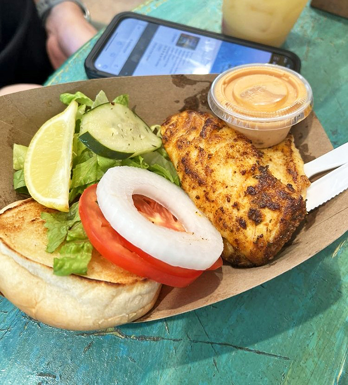 The blackened grouper sandwich arrives like seafood royalty, wearing a crown of fresh greens and demanding your complete attention.