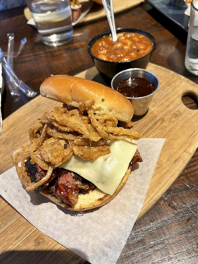The sandwich arrives like a meaty celebrity, accompanied by an entourage of crispy onion straws and beans studded with more burnt ends because too much of a good thing is just right.
