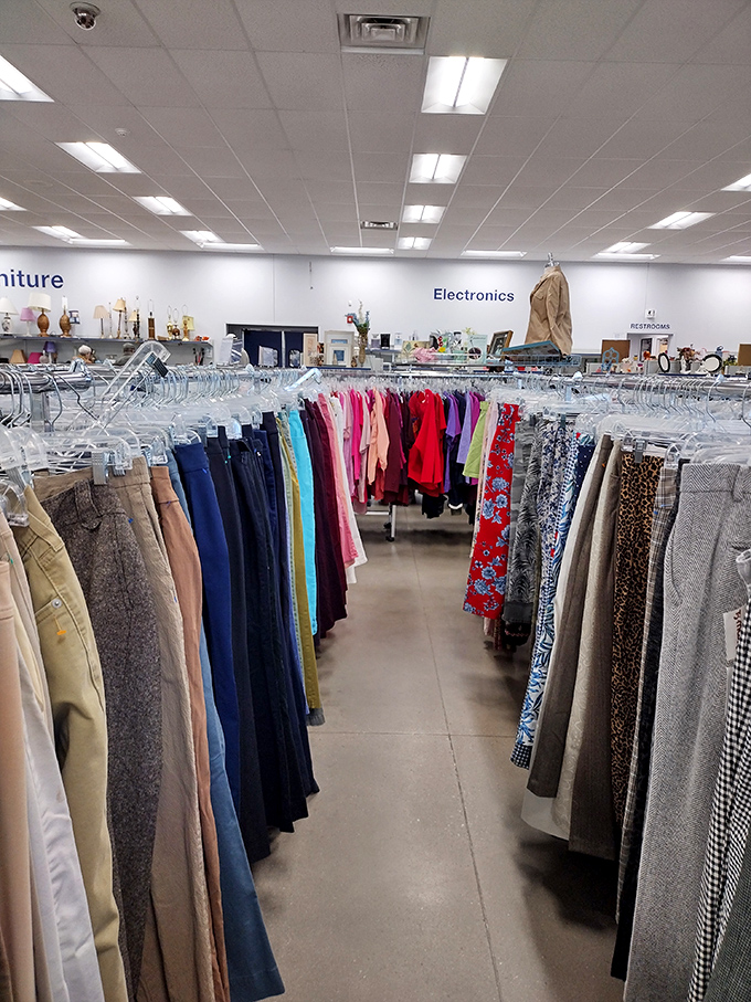 The clothing aisles stretch like a textile rainbow. Each garment holds stories from previous lives while waiting to join the next chapter of your wardrobe.