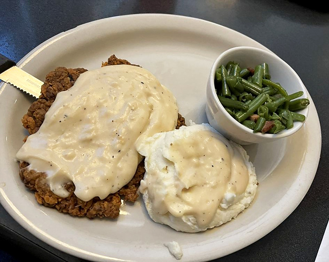 Country fried steak smothered in peppery gravy with eggs nestled alongside. Comfort food architecture at its most magnificent.