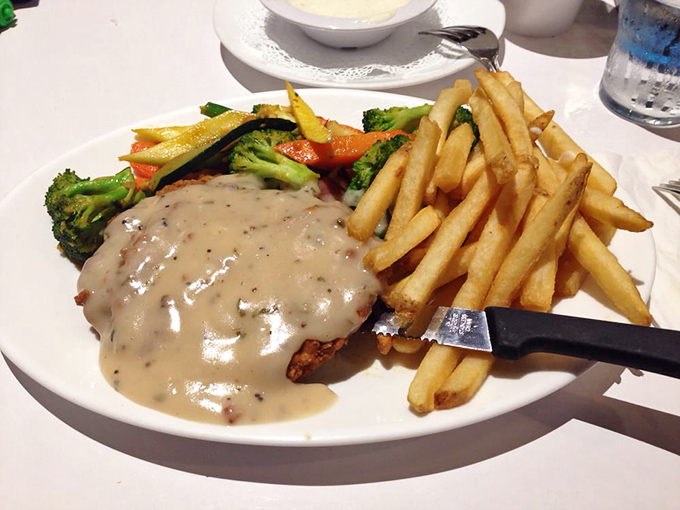 The holy trinity of diner perfection: golden-brown steak, crispy fries, and vegetables pretending they belong in this indulgent equation.