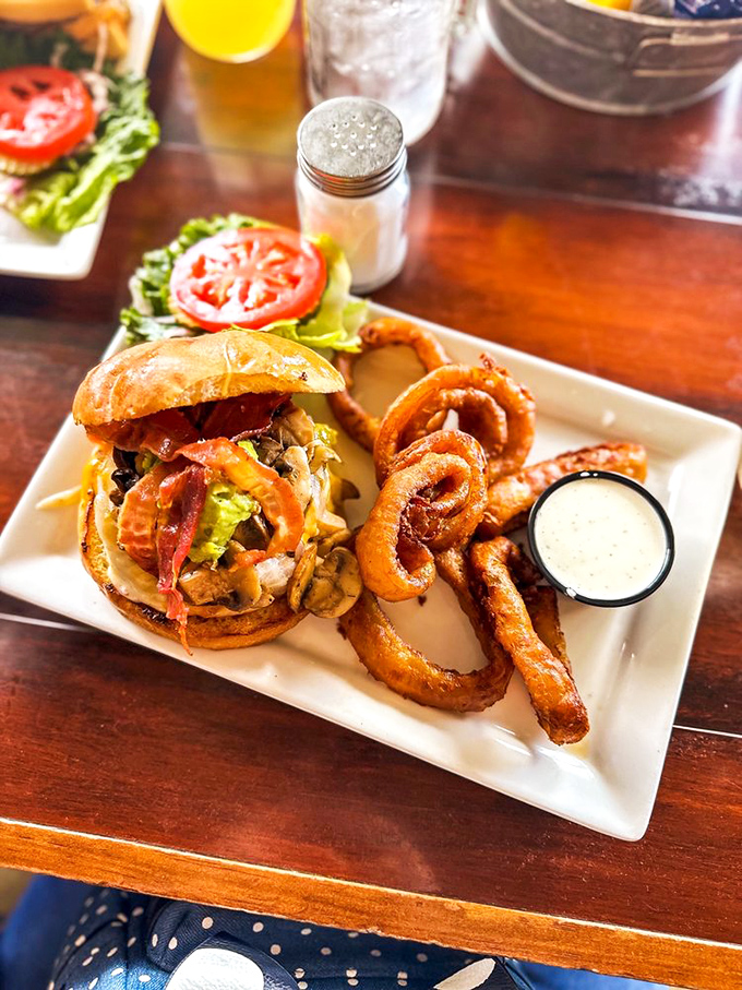 Onion rings so perfectly golden they deserve their own currency, paired with a burger that's dressed to impress—bacon included, no extra charge.