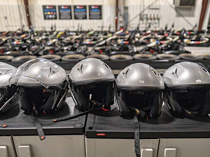 Helmets lined up like silver astronaut heads, waiting to protect the dreams of wannabe racers from reality's hard corners.