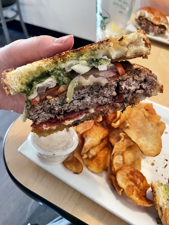 Cross-section perfection reveals the burger's soul. Those house-made chips are the unsung heroes of this plate—crispy, salty satisfaction.