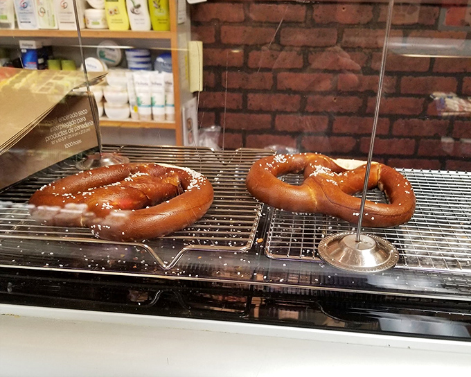 Fresh pretzels lounging on the rack, glistening with salt crystals like they're sunbathing on a Bavarian beach. 