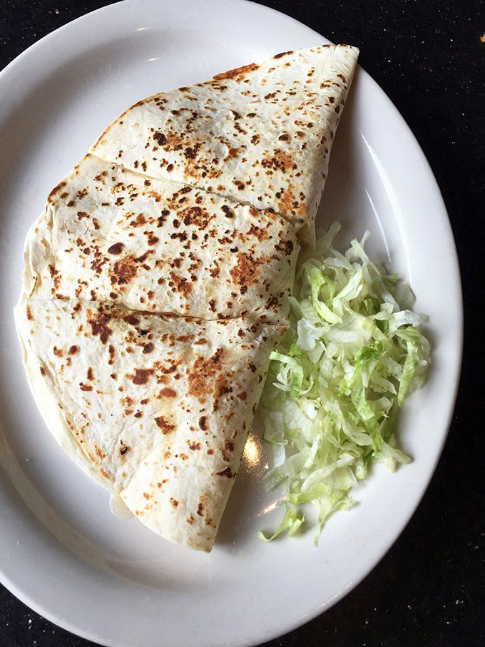 Quesadillas reaching their final form&mdash;crispy-edged, stuffed with cheese that pulls apart in dramatic fashion, and served with that essential bed of shredded lettuce.