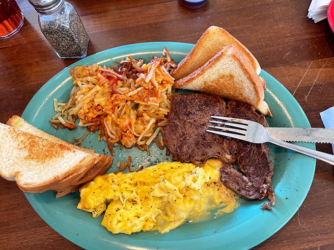 Morning indulgence, diner-style: perfectly seasoned ribeye meeting fluffy scrambled eggs while hash browns wait patiently for their moment.