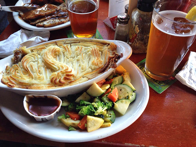 The holy trinity of pub dining: a perfectly crafted shepherd's pie, fresh vegetables, and a pint of something amber. Heaven exists and it's on this plate.