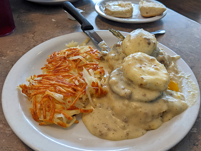 Breakfast architecture at its finest &ndash; a savory foundation of biscuits crowned with poached eggs and smothered in creamy gravy alongside crispy hash browns.