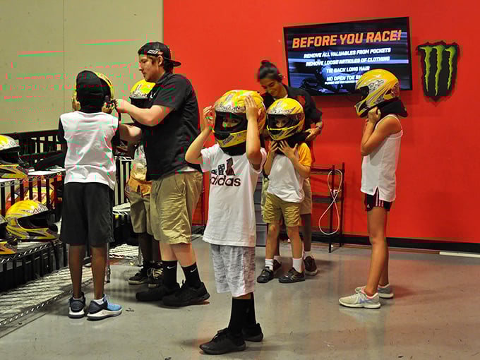 Safety first! Staff members ensure young racers are properly helmeted before hitting the track. That pre-race face says, "I'm about to make Dad eat my dust." 