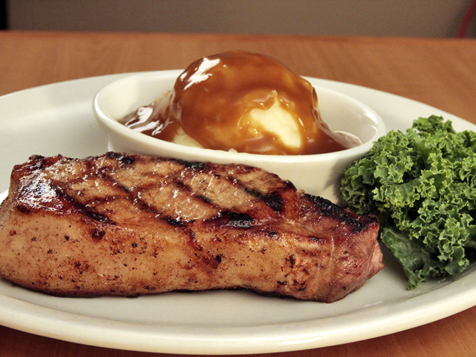 This isn't just a strip steak; it's a declaration of independence from boring dinners, flanked by a baked potato that's practically wearing a tuxedo.