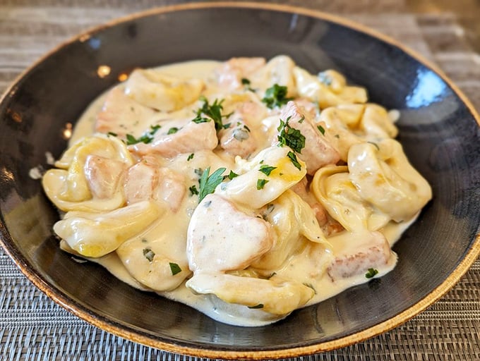 Tortellini al salmone that looks like it's floating in a cream sauce so velvety it could double as a pillow for tiny pasta angels.