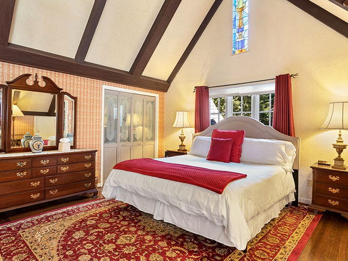 Bedroom goals that make you question every design choice you've ever made. That cathedral ceiling and splash of red say "romance novel cover" in the best way.